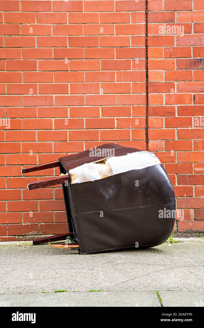 Bucket chair with broken leg abandoned in a street Stock Photo - Alamy