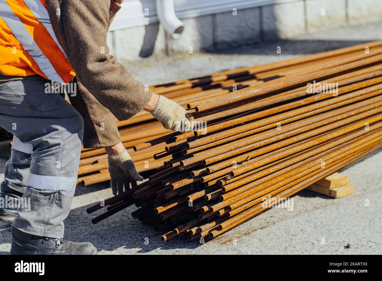 Slinger stacks thin metal pipes in stack on construction site. Close-up ...