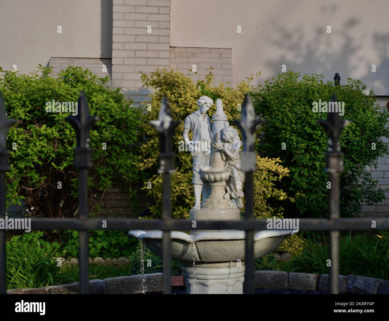 A white sculpture with a male and female on an empty fountain behind ...