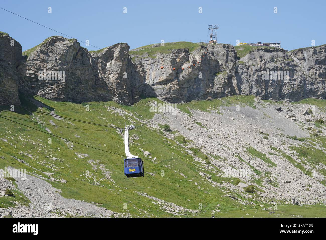 Blue passenger ropeway cabin running to the peak of mountain in ...