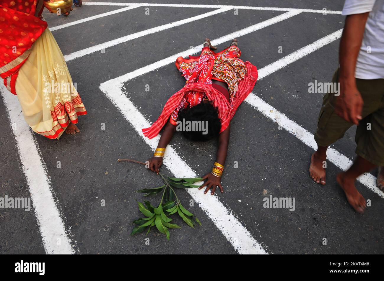 A Indian woman lying prostrate worshiping the Sun god during Chhat puja ...