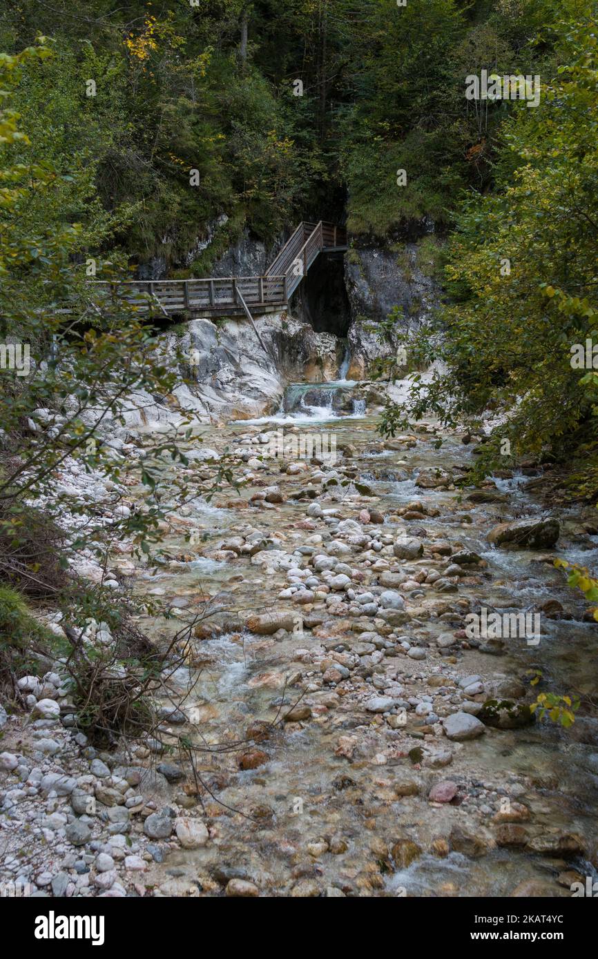 A vertical shot of a shallow river flowing among rocky land surrounded ...