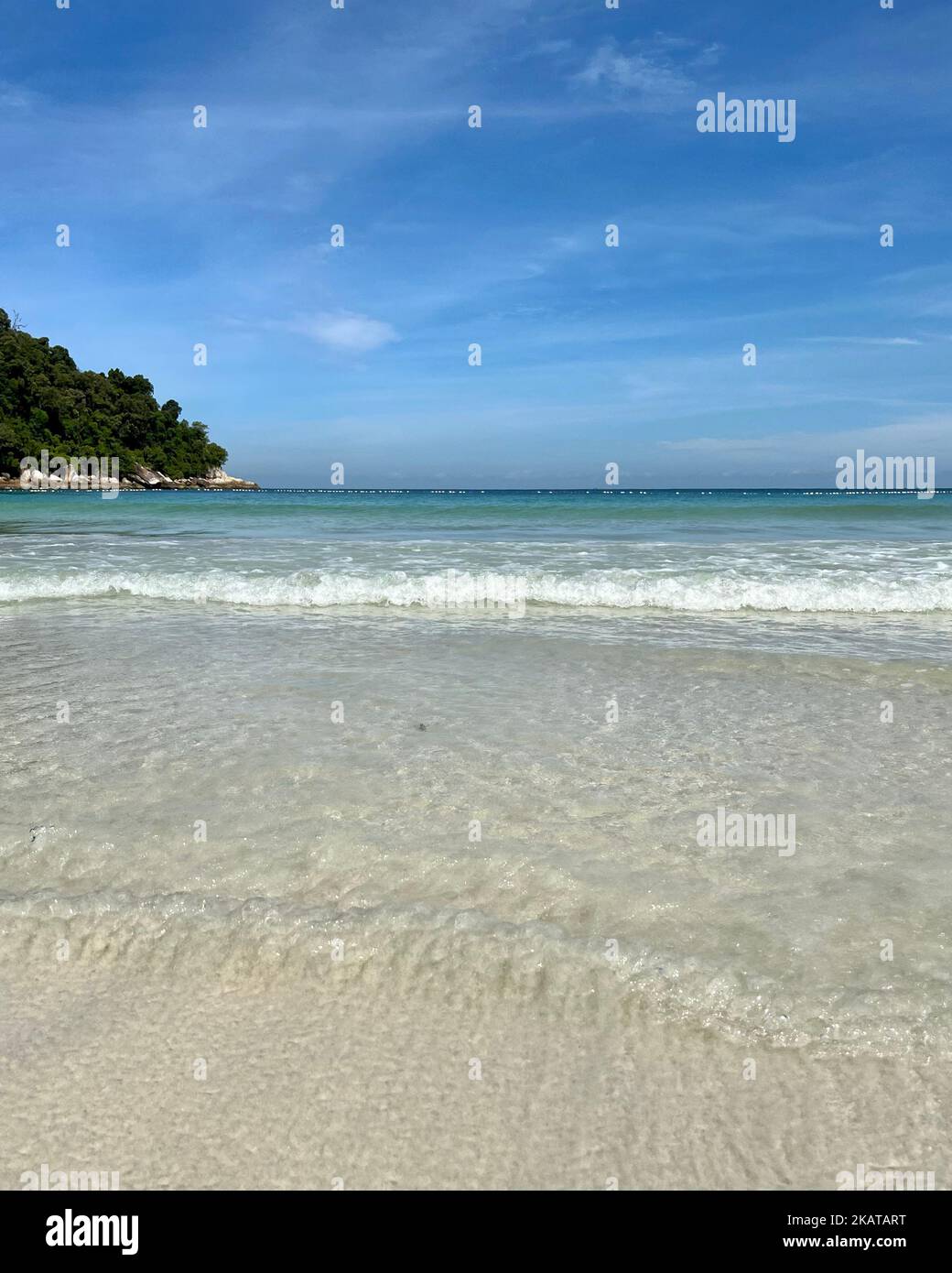The vertical view of ocean waves reaching the sandy shore under the ...