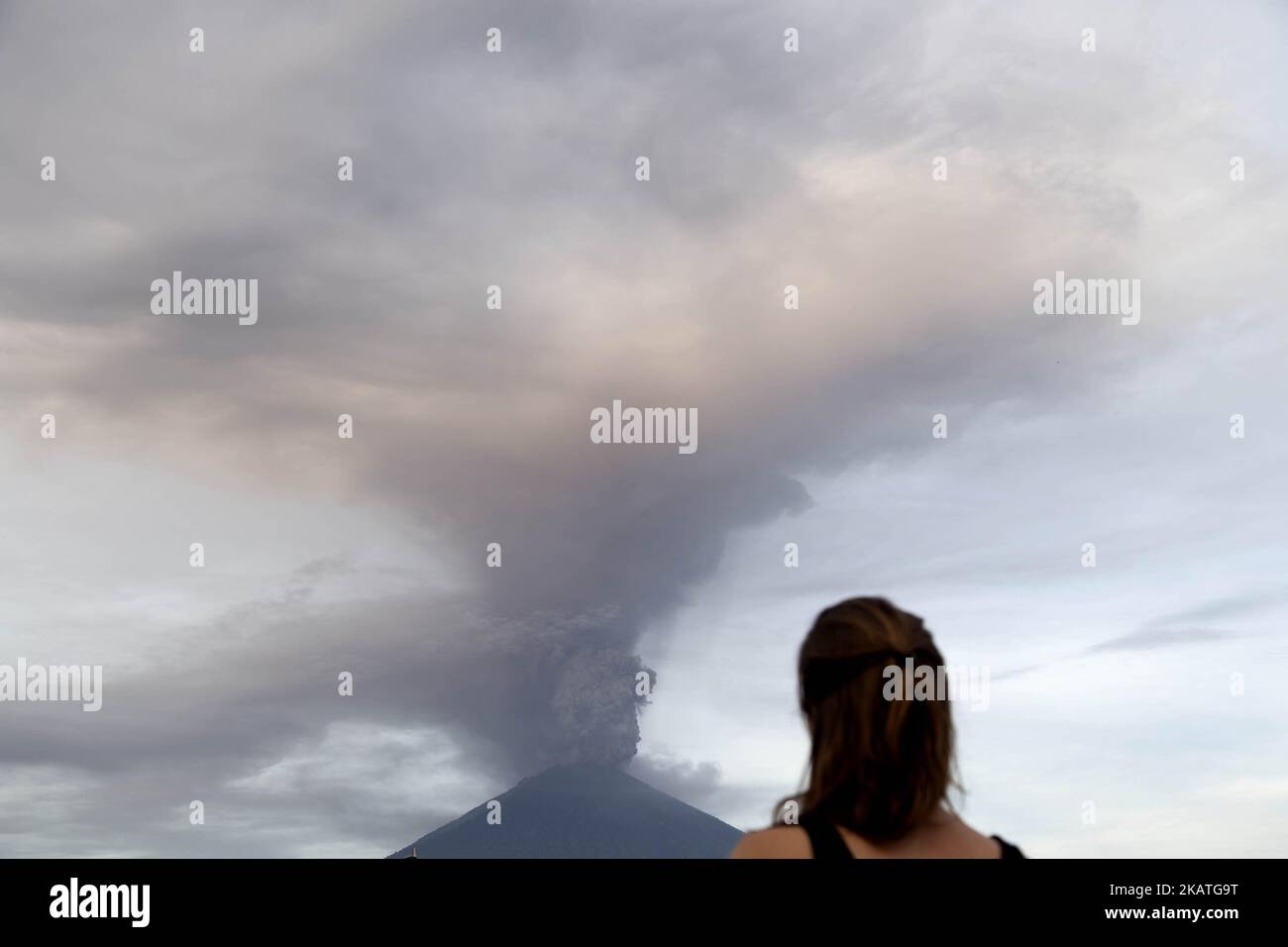 Mount Agung sends a dark ash cloud into the sky, as seen Amed Beach in ...