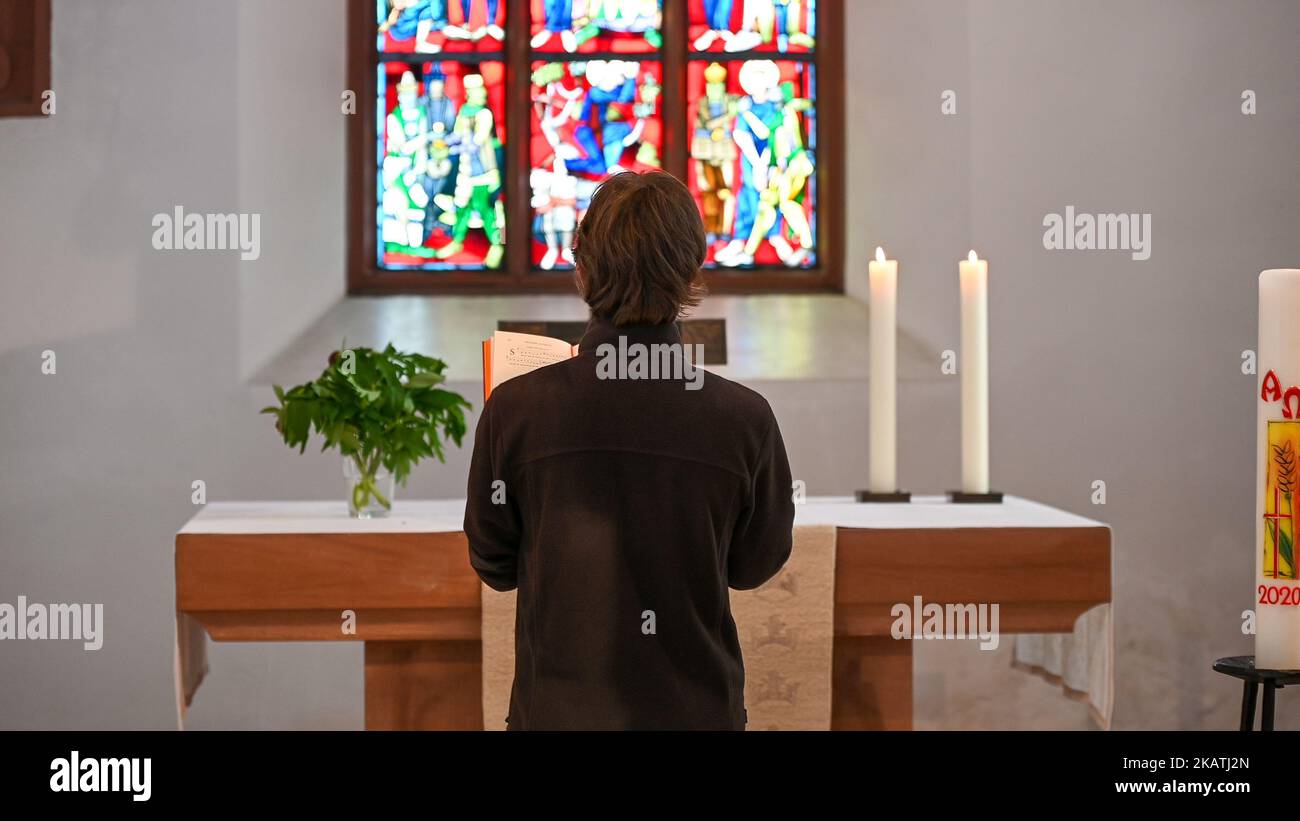 A back view of a young man praying at the altar in a church Stock Photo ...