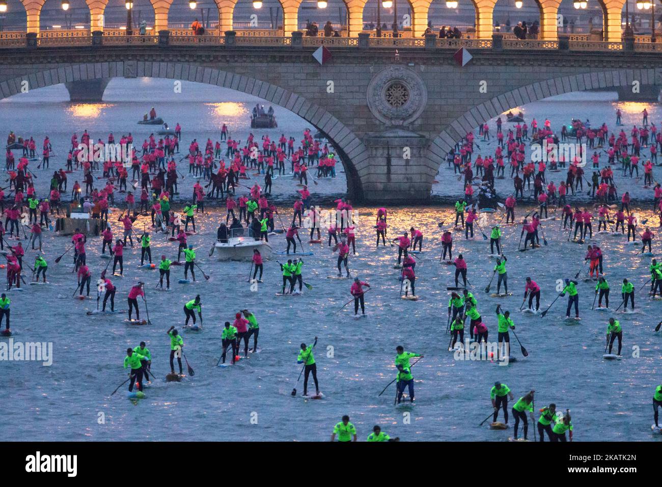 Paddle boarders pass near the Pont de Bercy bridge as they participate ...