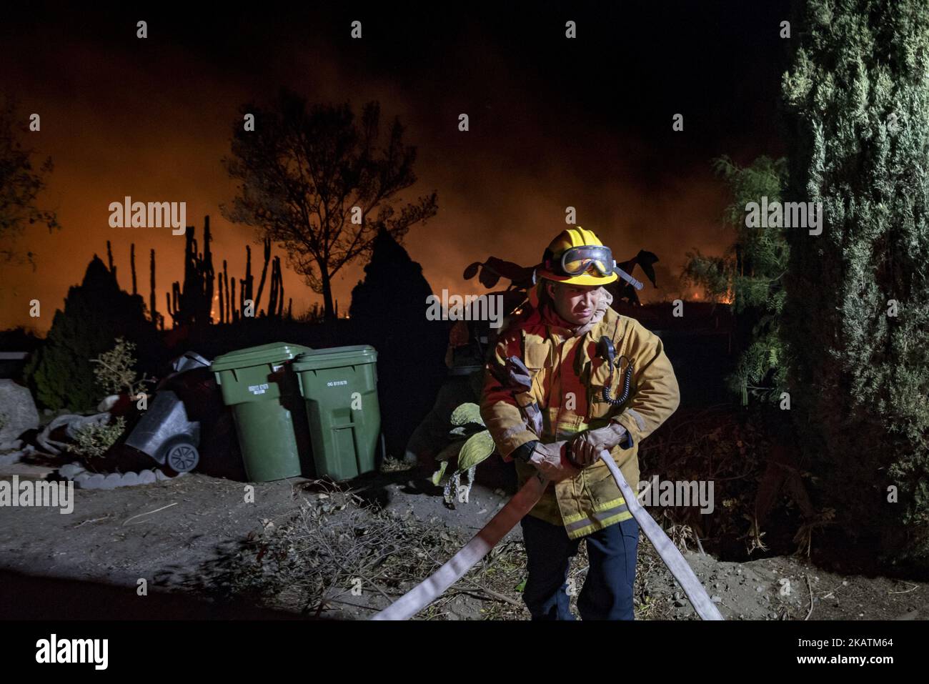 Firefighter works to defend homes from an approaching wildfire in Los ...