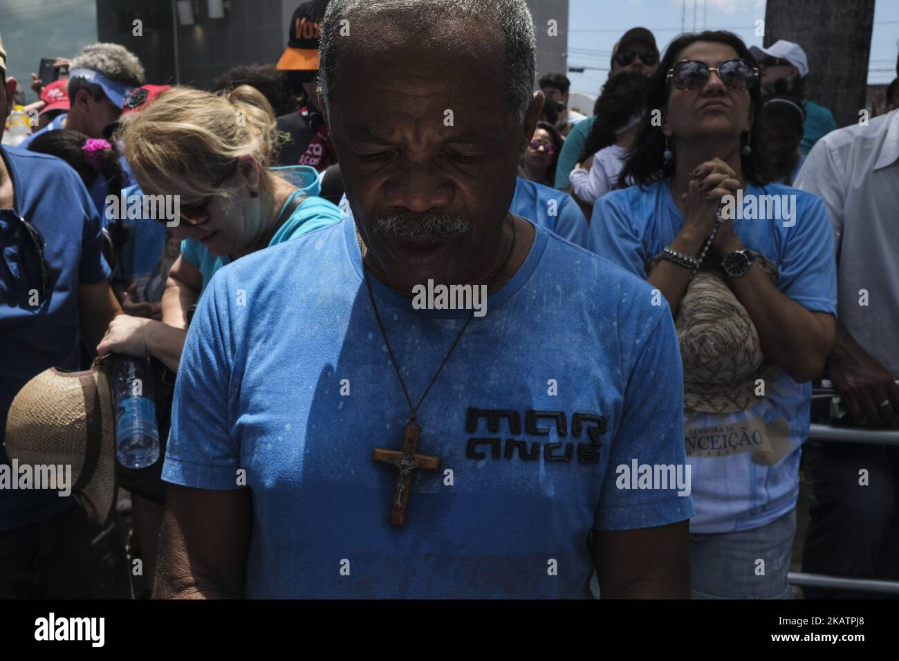 A man with a crucifix seems to pray at the foot of the image of the ...