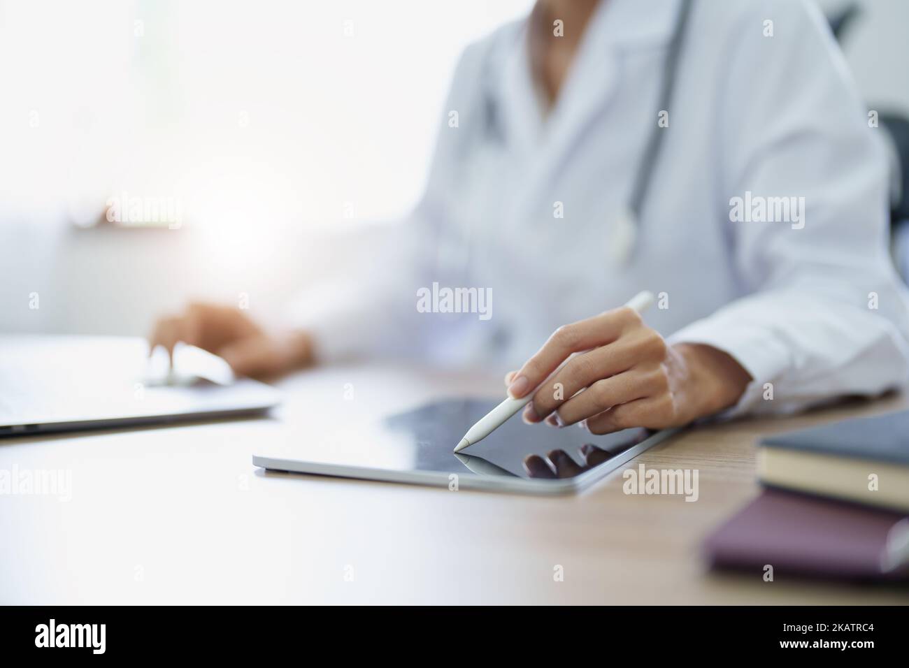 Portrait of an Asian female doctor using a computer and tablet to work ...