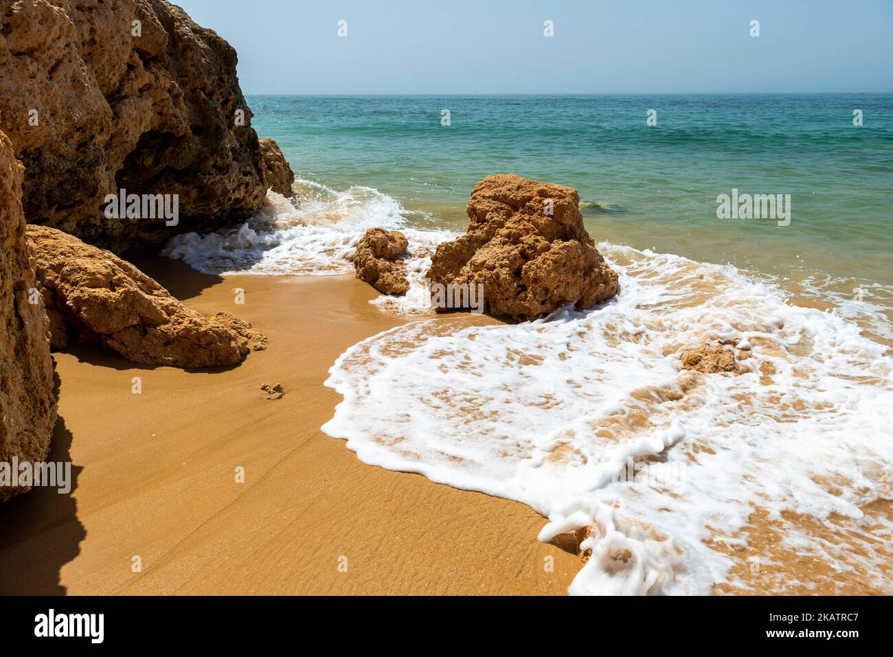 An aerial shot of a beach with cliffs and stones and waves washing the ...