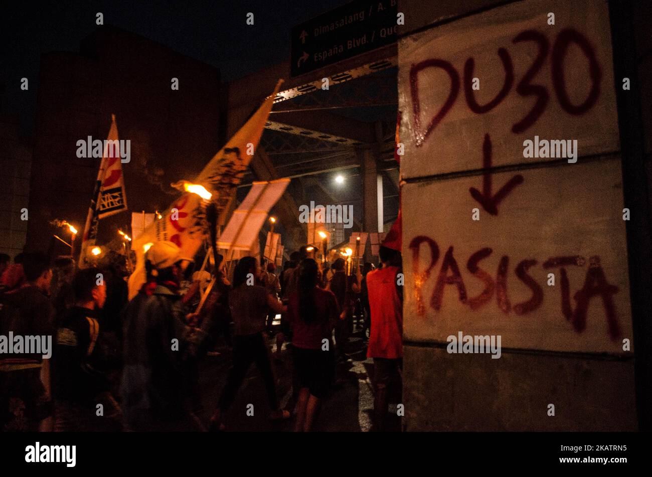 Protesters carry placards and torches as they march from Bonifacio ...