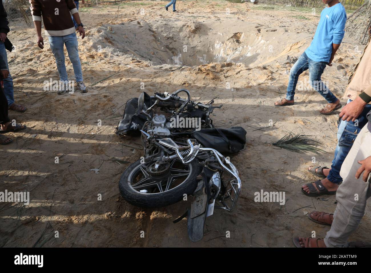Palestinians inspect the damaged remains of a motorcycle, that was ...