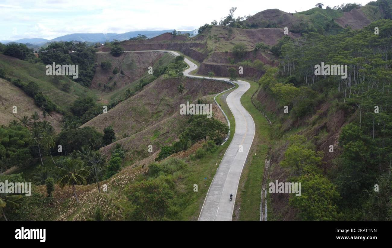 A beautiful view of a road on a hill with green trees Stock Photo - Alamy
