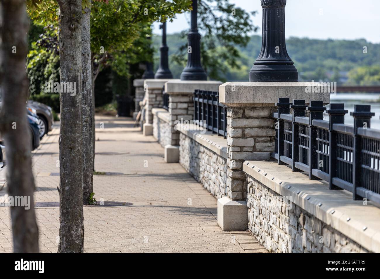 A selective of stone wall with metal light posts and railings between a ...
