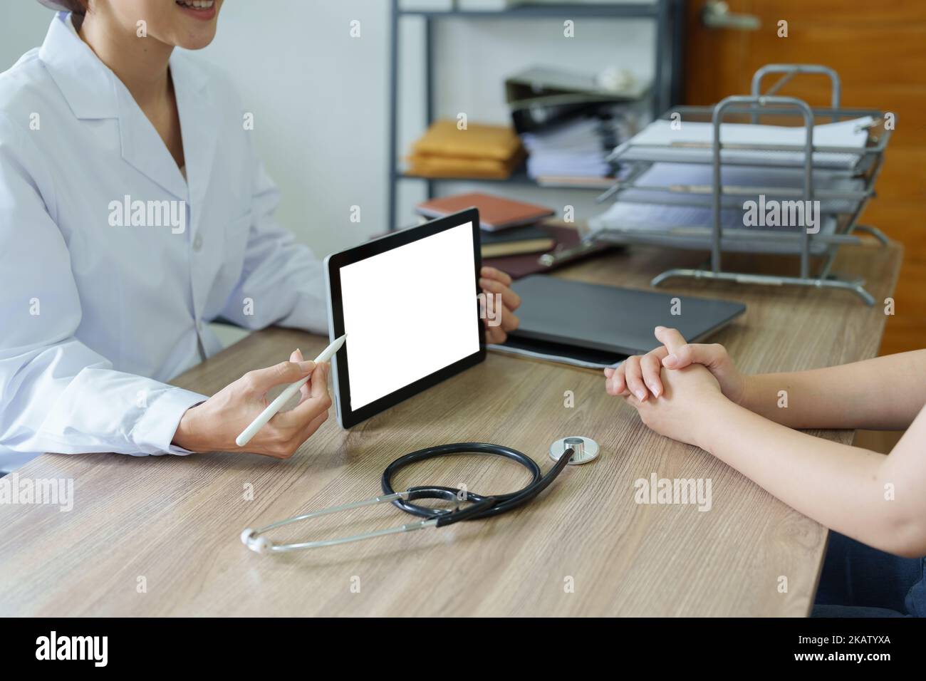 Asian female doctor holds computer tablet to customer, white screen can ...