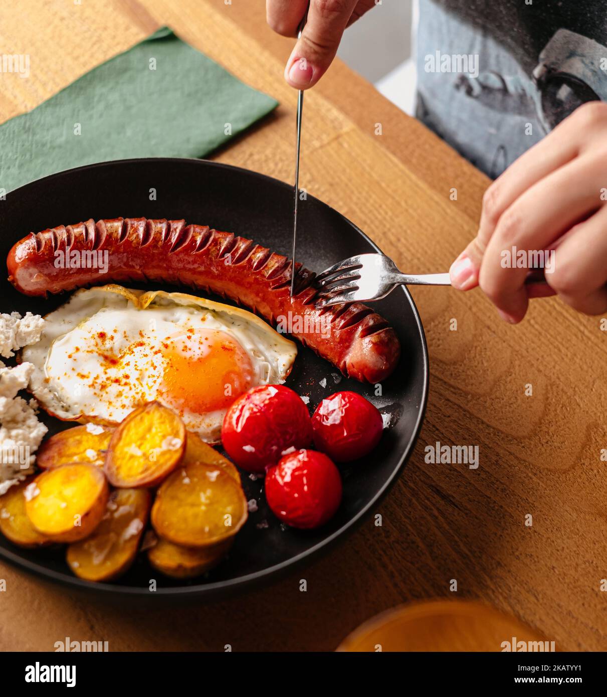 A breakfast plate with a woman cutting the sausage Stock Photo - Alamy