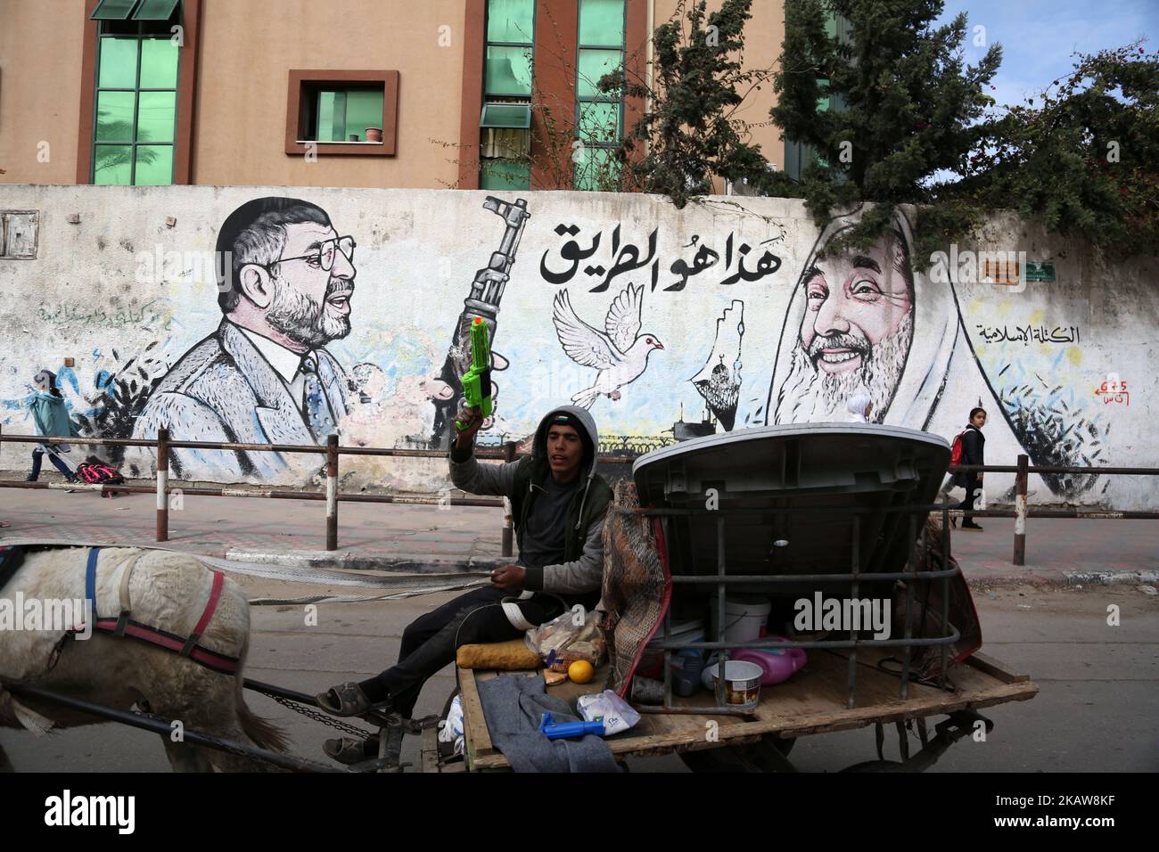 Palestinian walk past graffiti of Hamas late leader Sheikh Ahmad Yassin ...