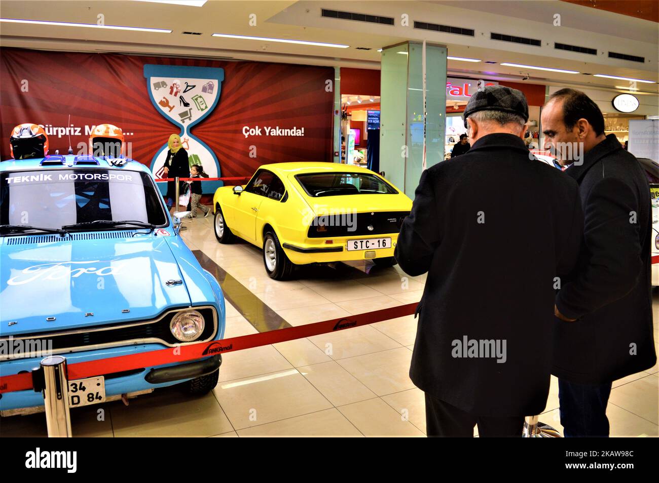 Two men stand near racing automobiles as retro cars, gears and ...