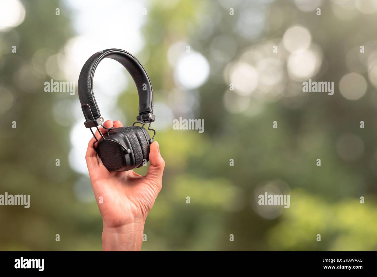 Headphones in hand on nature background. Banner for meditation sounds ...