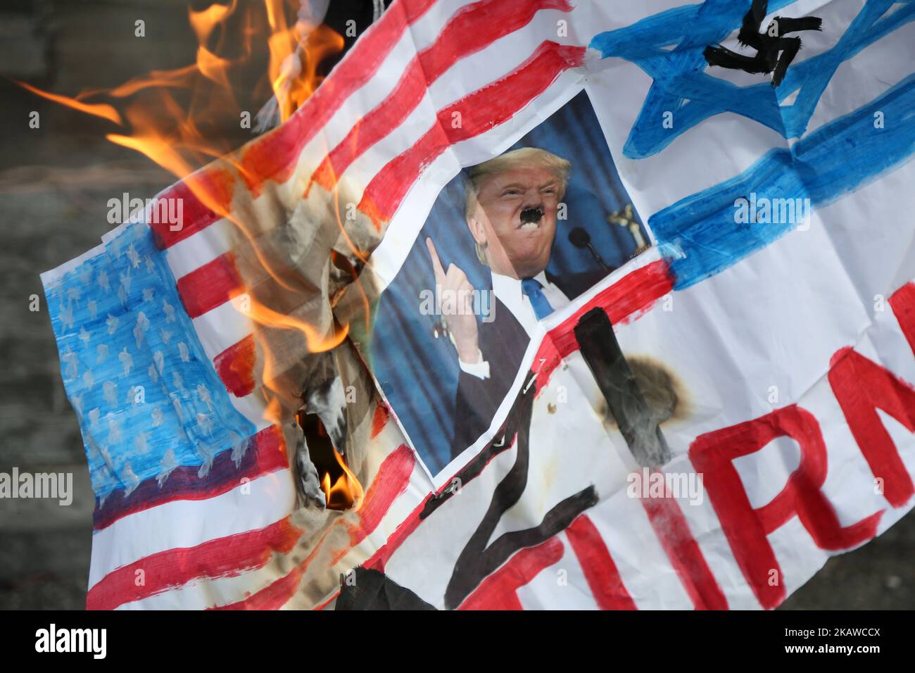 A Palestinian demonstrator holds a pistol as he burns representations ...