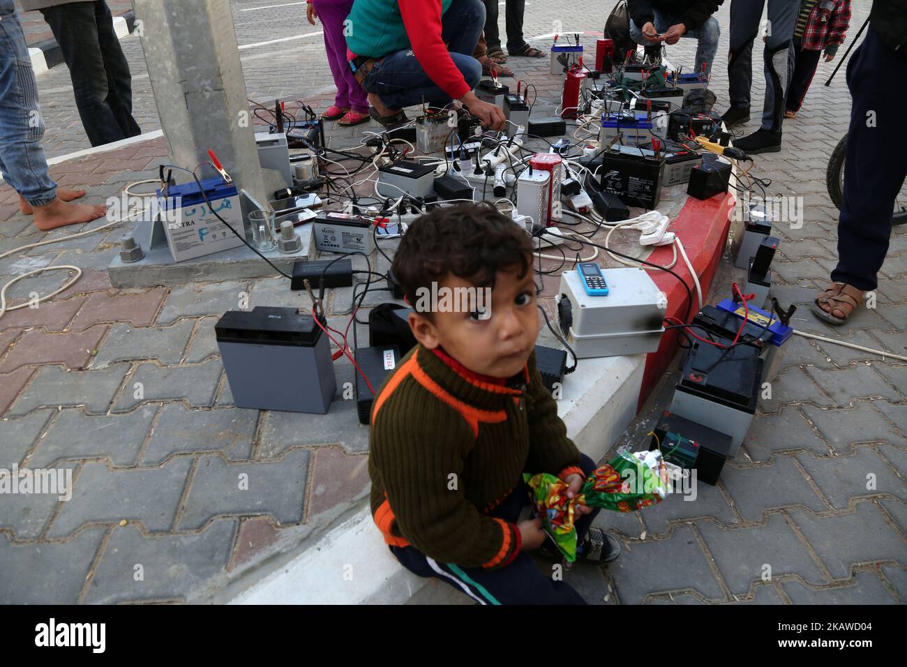 A Palestinian man charges his mobile phone from batteries offered as a ...