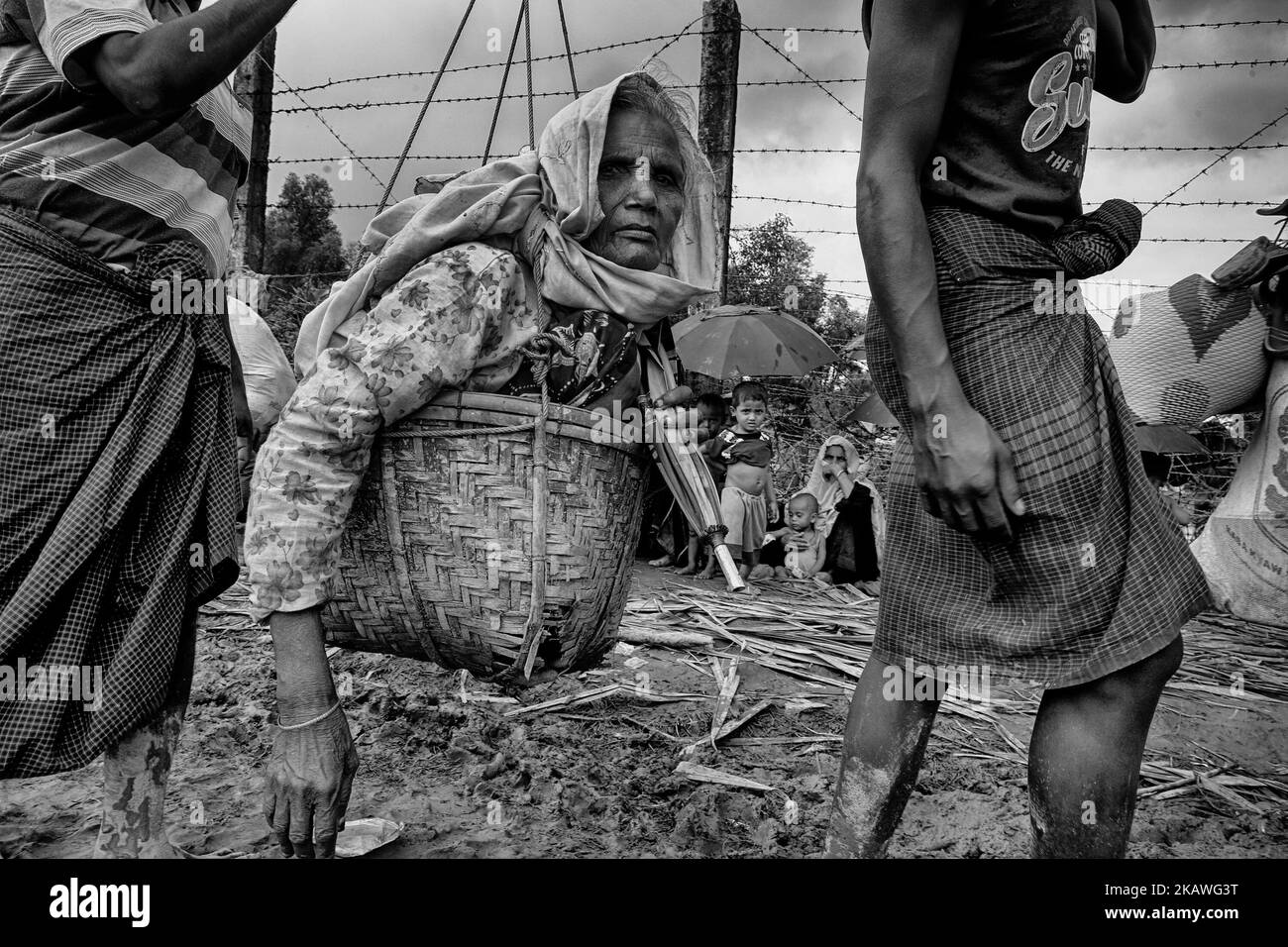 A rohingya woman is carried in a sling while crossing the myanmar ...