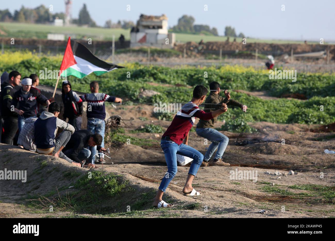 Palestinian protesters throw a rock toward Israeli soldiers during ...