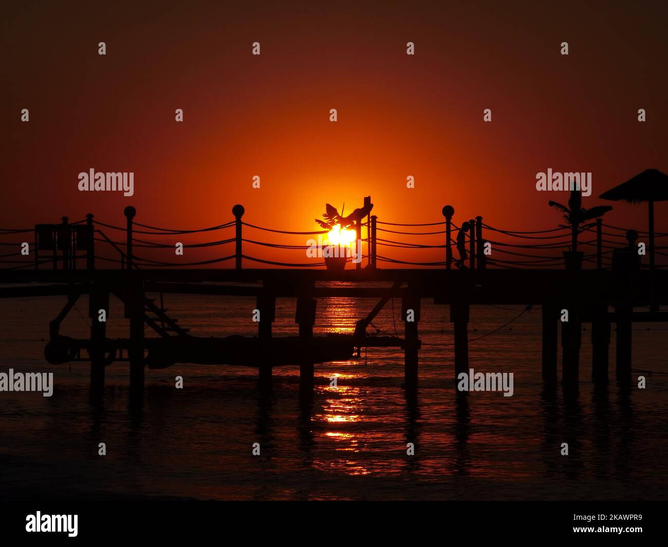 A beautiful sunset at a dock with the sunlight reflected in the water ...