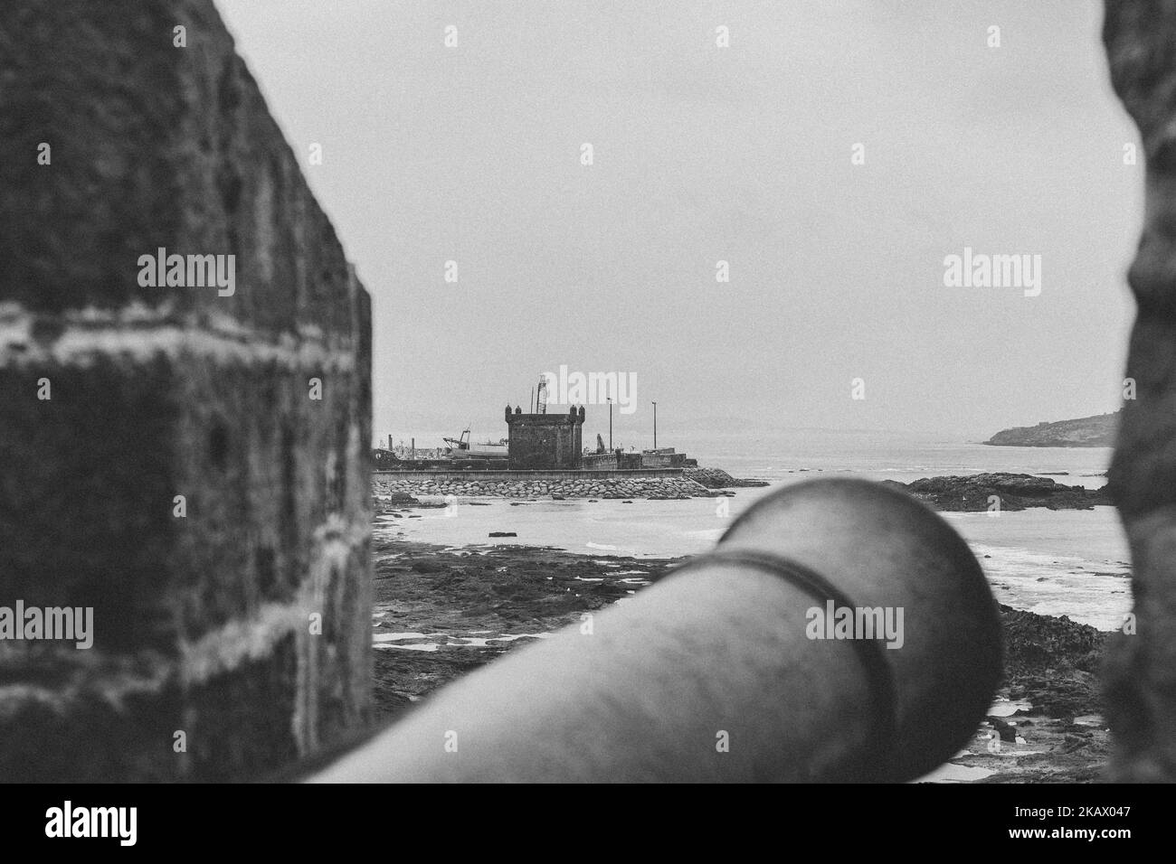 The grayscale view of an old cannon hidden in the walls of a coast ...