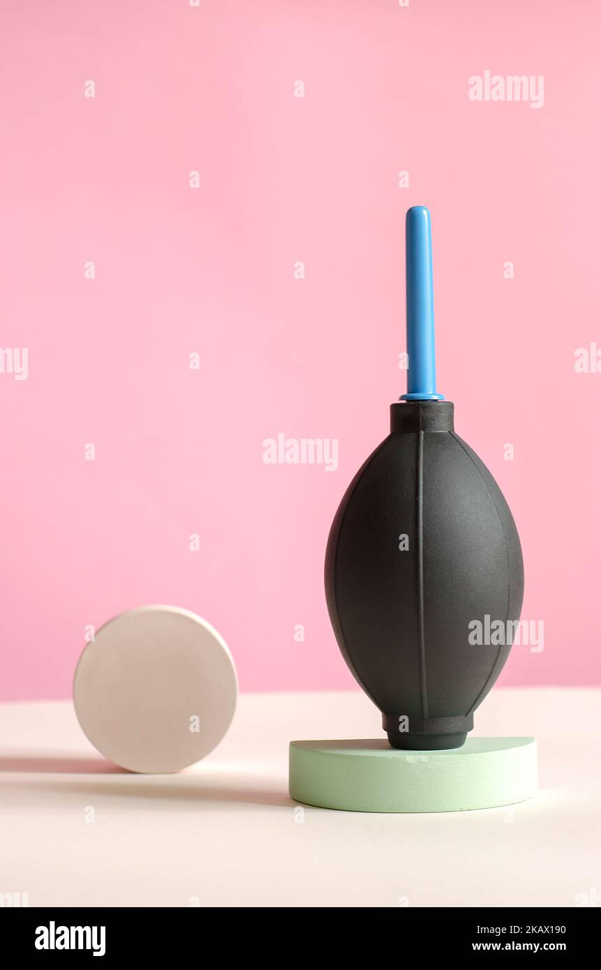 Black duster on a round podium on a pink background. Dust blower for ...