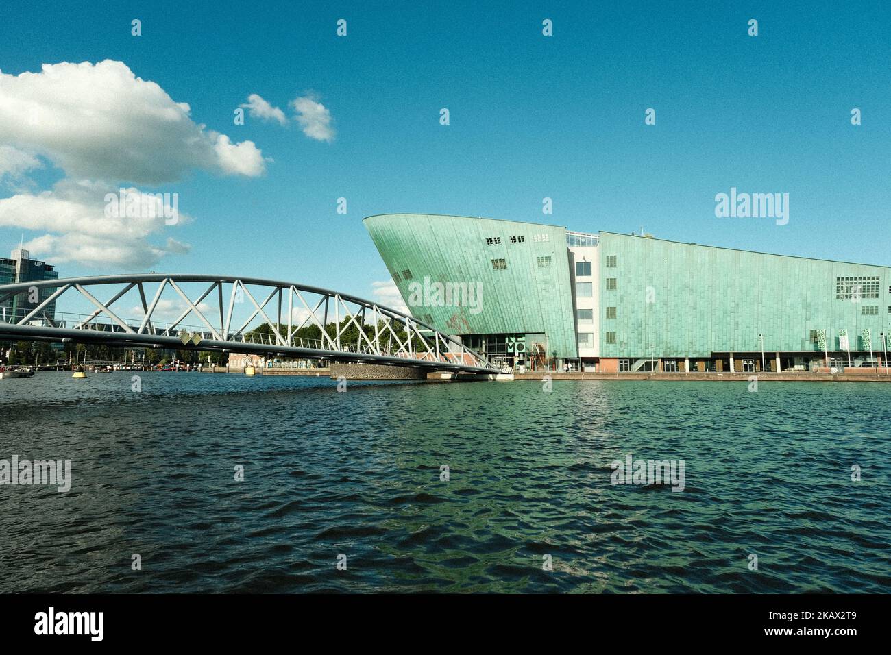 A waterside view of the NEMO science museum building under the blue sky ...