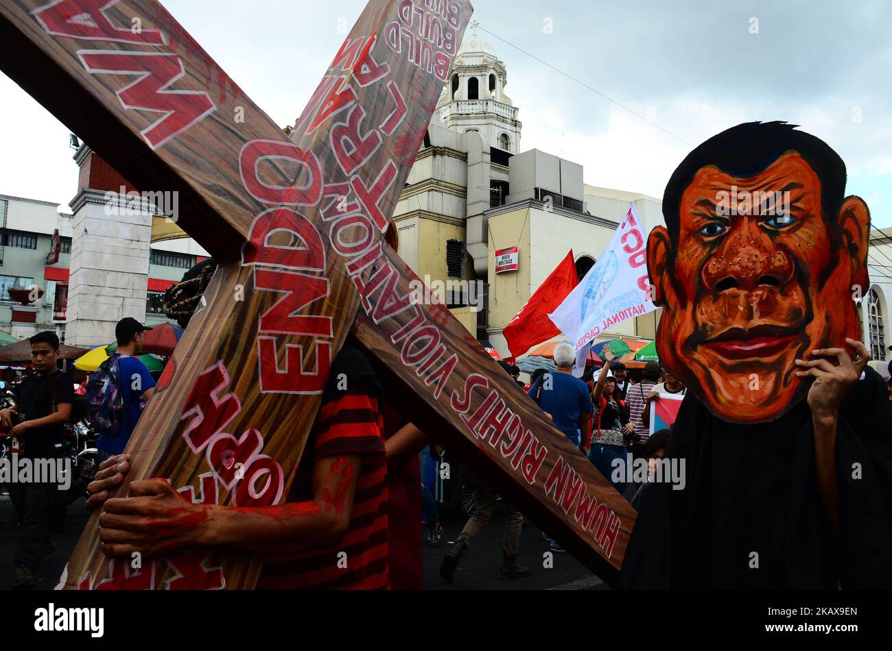 An activist imitating Jesus Christ carries a cross painted with red ...