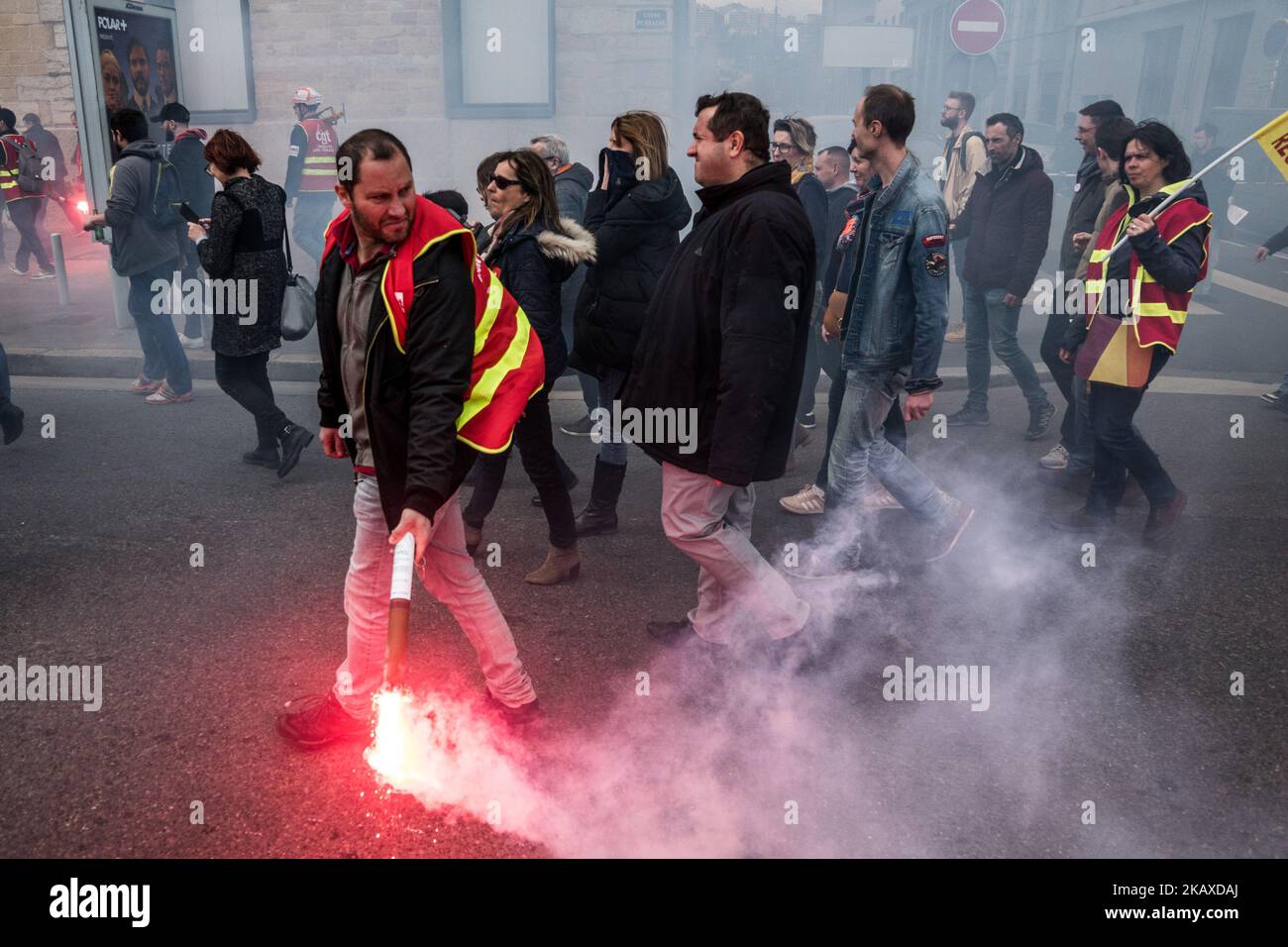 Protesters of SNCF employees hold up a banner and ignited flares during ...