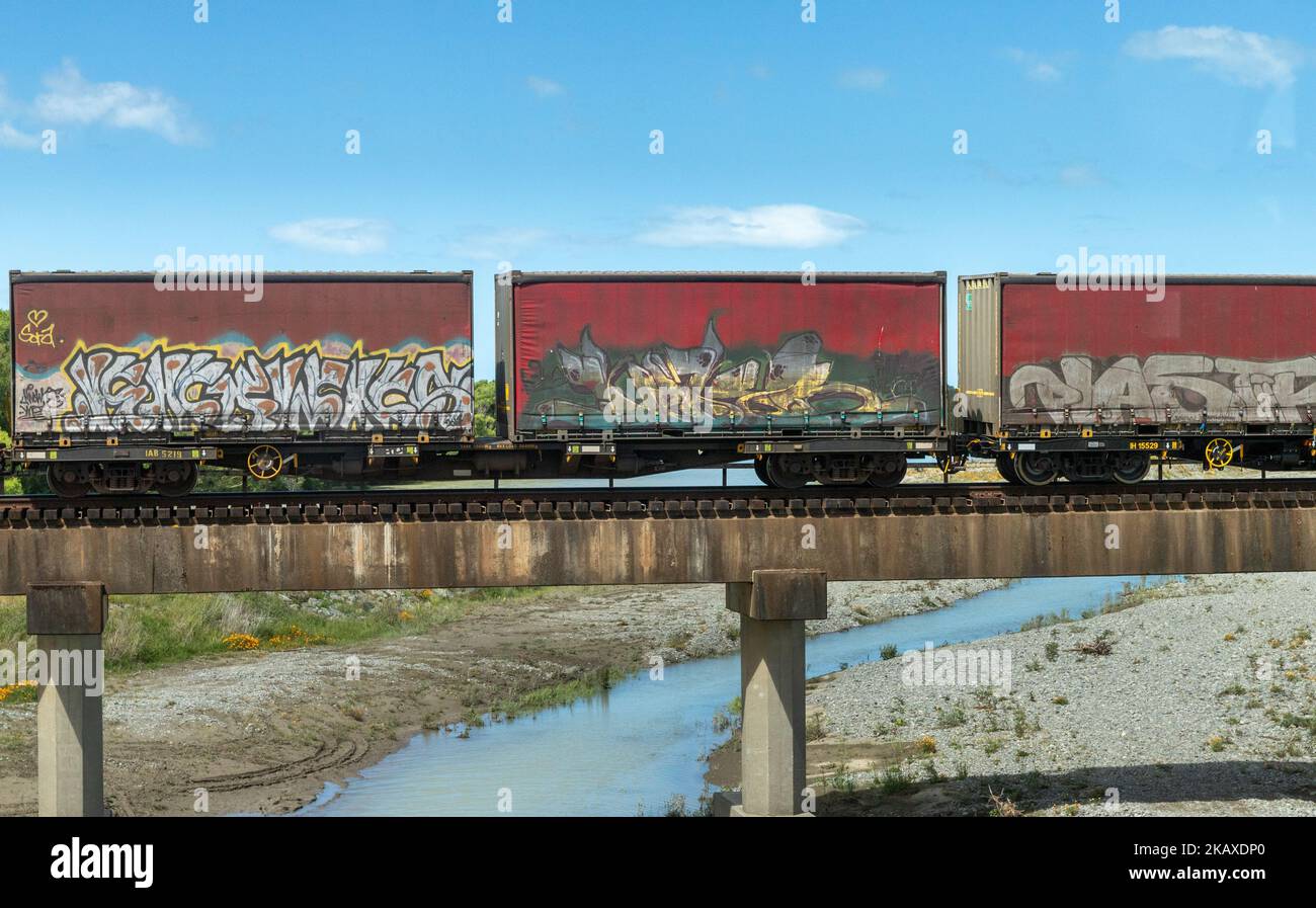 Street graffiti on containers on a cargo train over a blue background ...