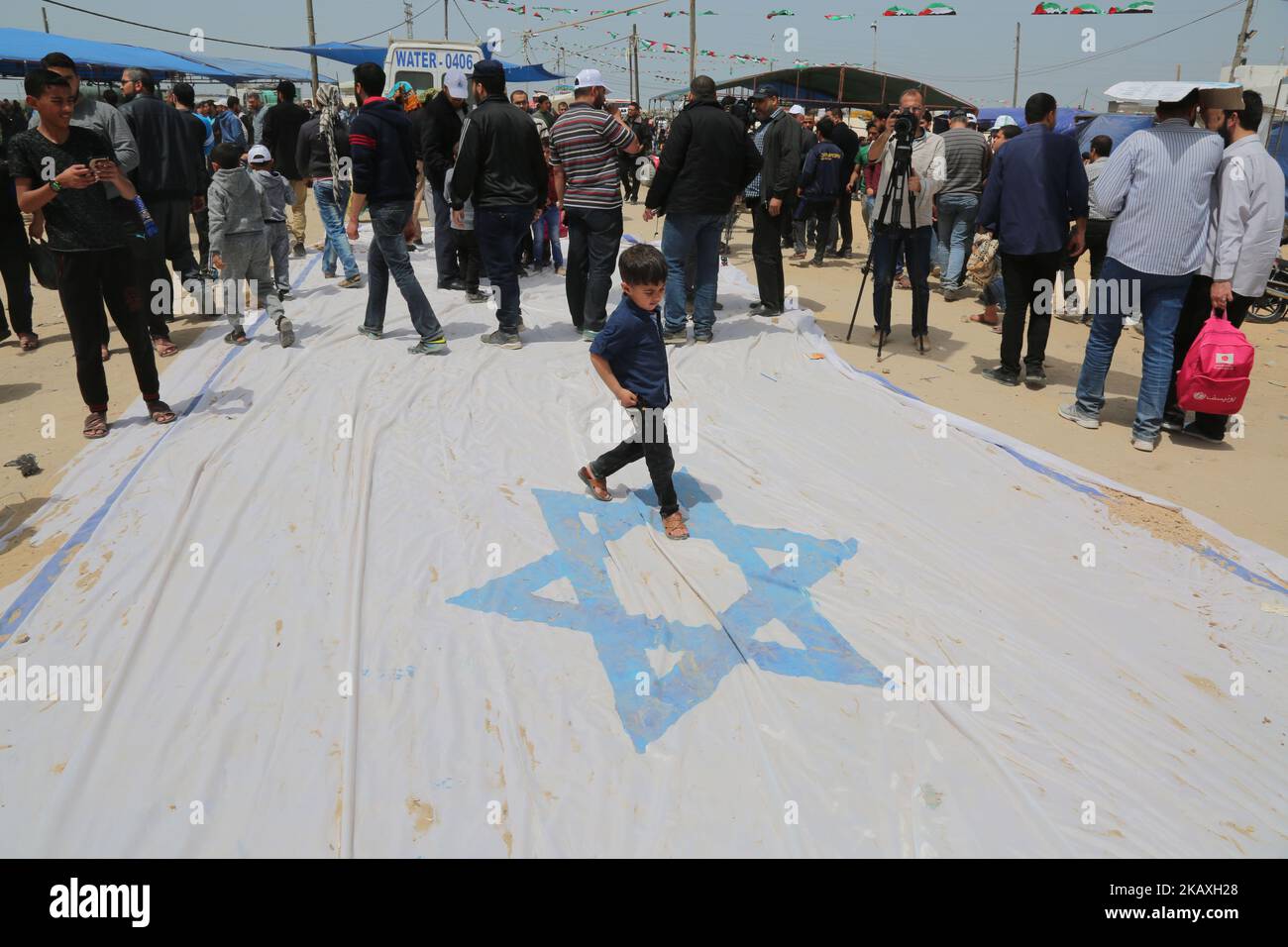 Palestinians walk on an Israeli flag during a protest demanding the ...
