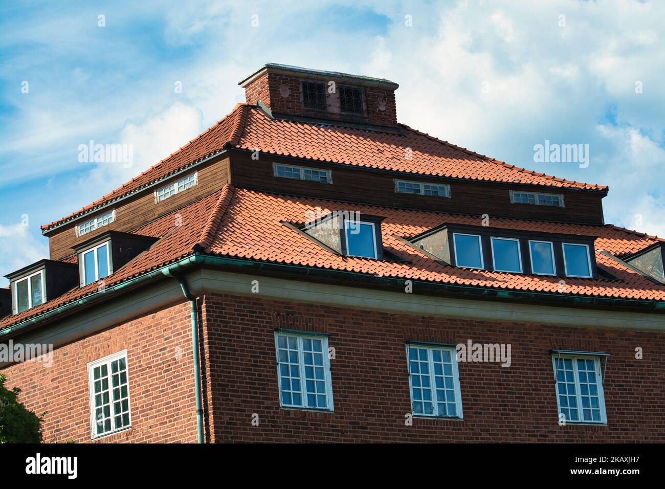 A view of a brick house frontage with windows under the half-cloudy sky ...