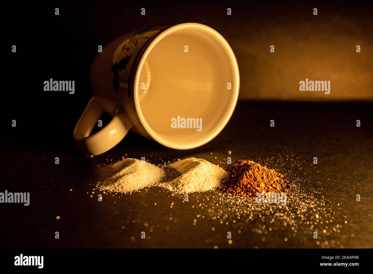 A close-up of a fallen cup around pile of coffee, sugar and powdered ...