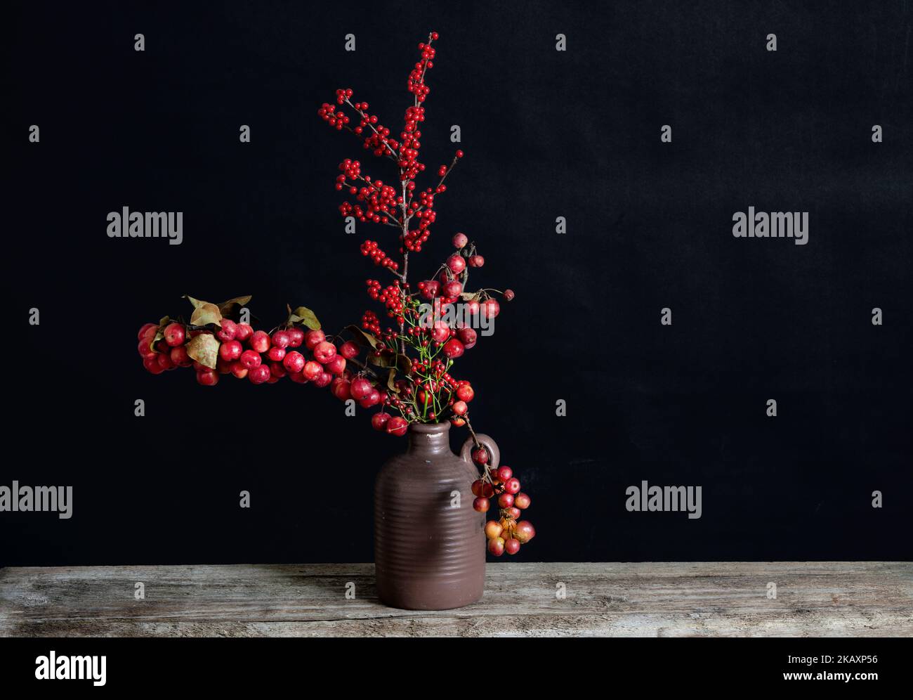 Branches of ornamental apple and Ilex in brown vase Stock Photo - Alamy