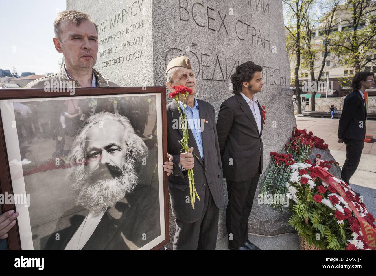 Man holds a huge photo of Karl Marx under his memorial statue during ...