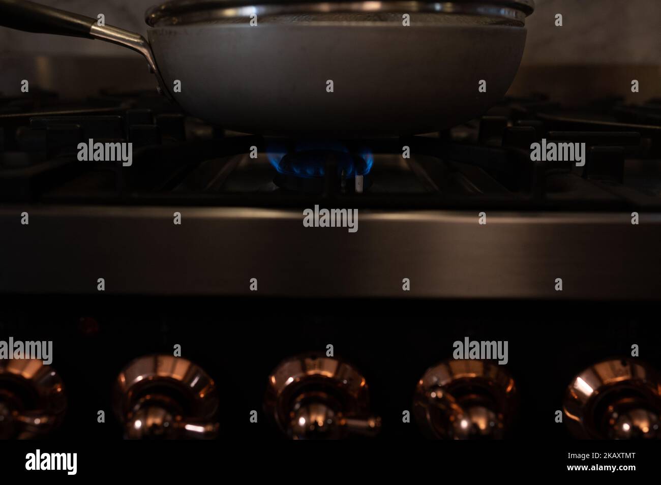 A medium gray frying pan sits on top of a light gas stove Stock Photo ...
