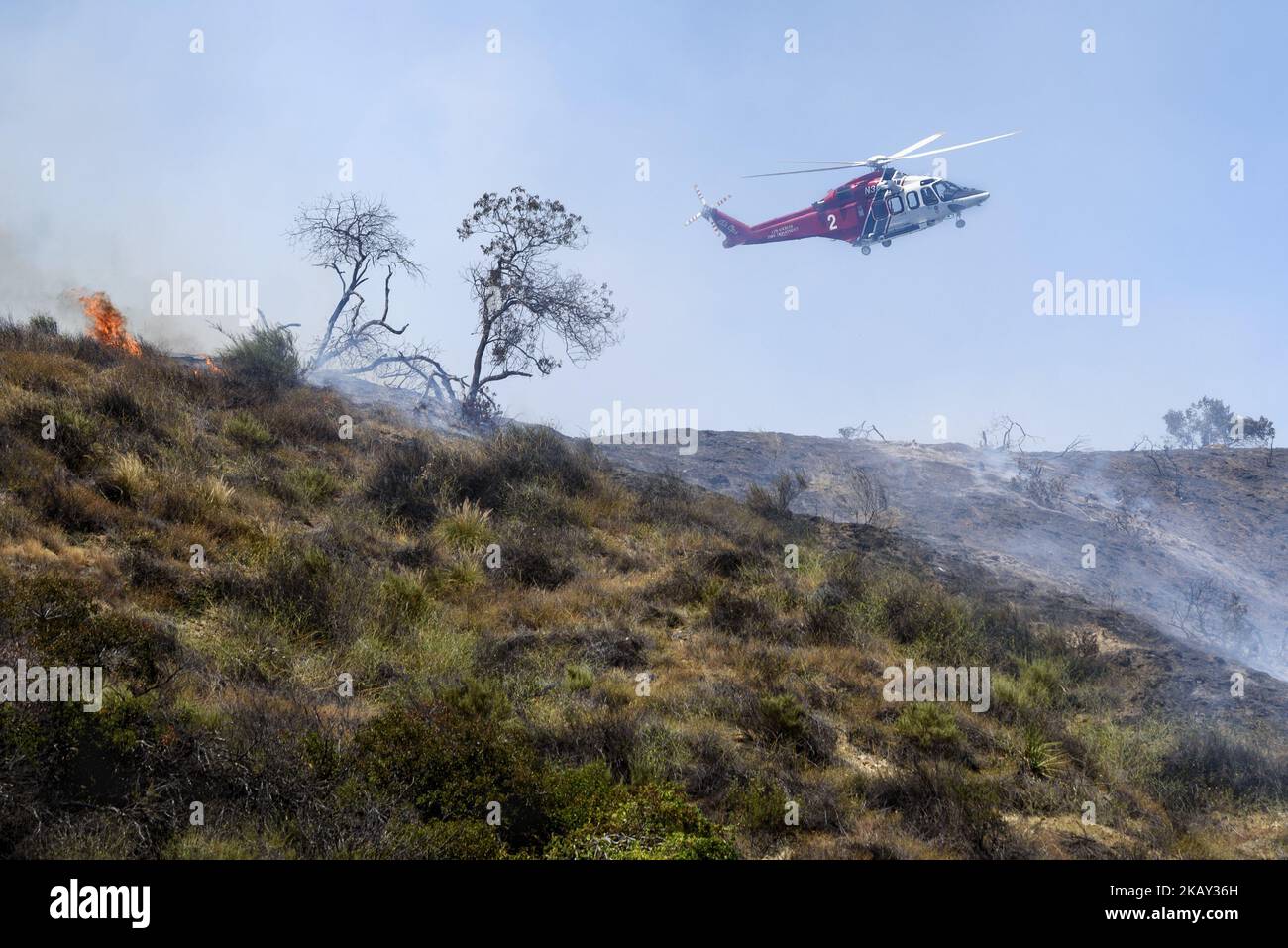 A firefighting helicopter makes a water drop over a brush fire in ...