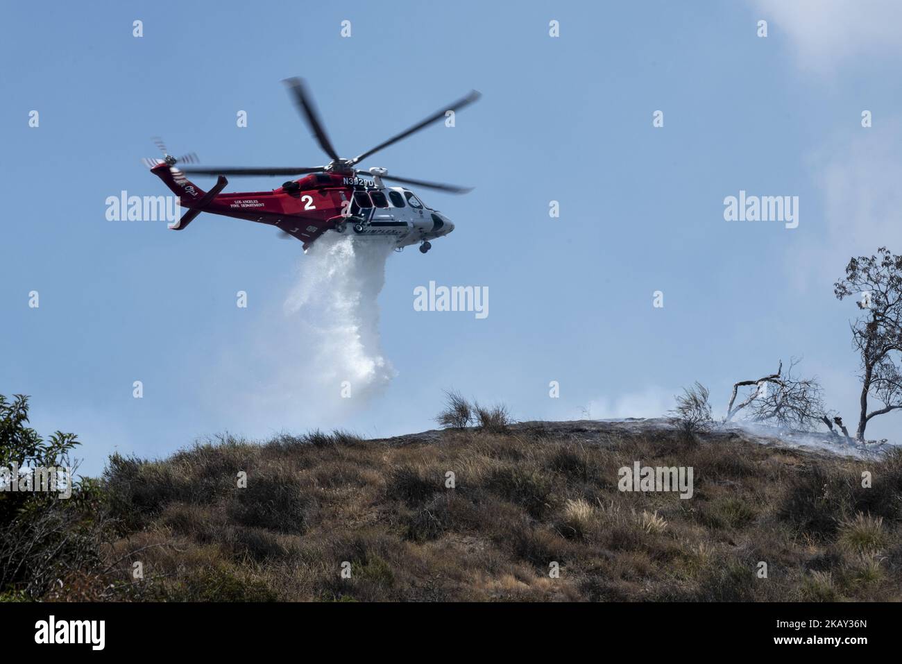 A firefighting helicopter makes a water drop over a brush fire in ...