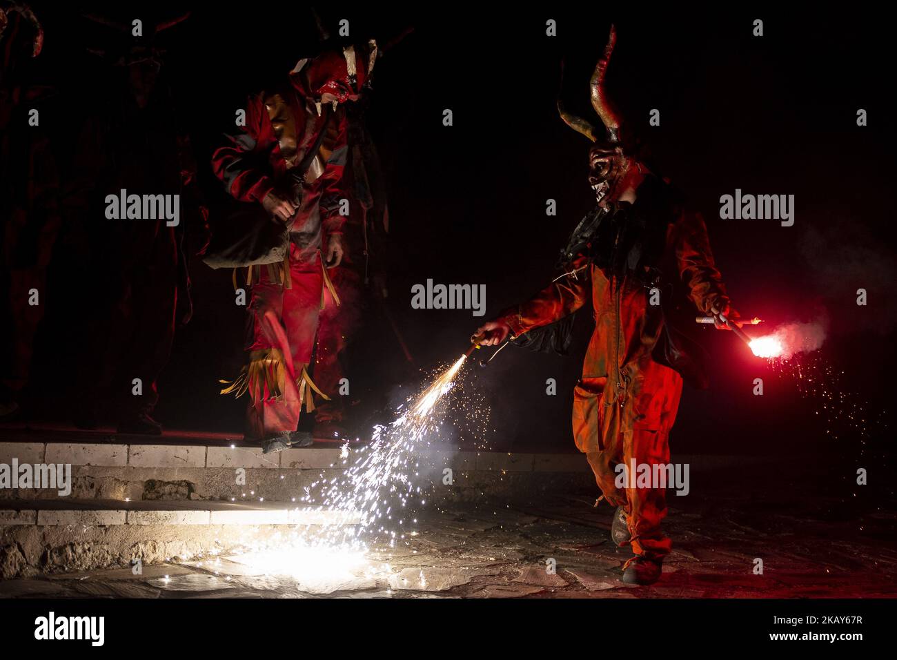 A person dressed as a devil carrying a torch walks amongst the crowd ...