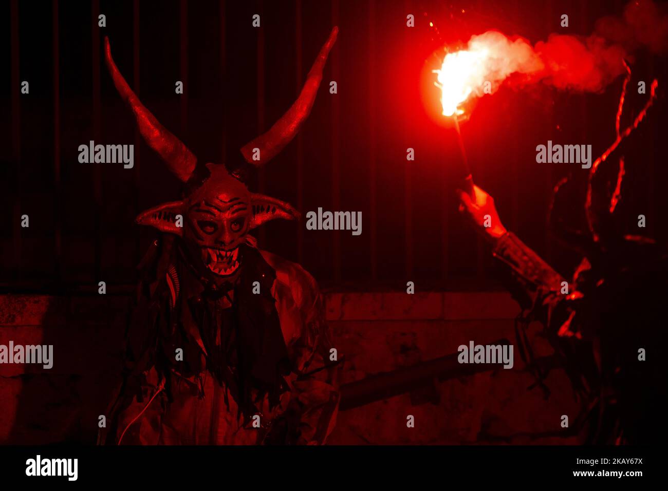 A person dressed as a devil carrying a torch walks amongst the crowd ...