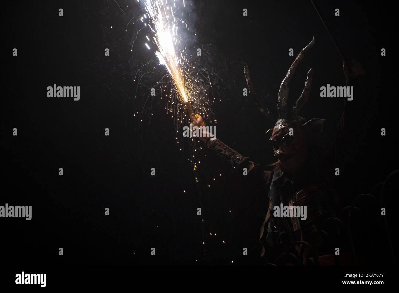 A person dressed as a devil carrying a torch walks amongst the crowd ...