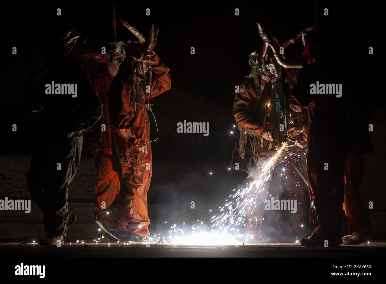 A person dressed as a devil carrying a torch walks amongst the crowd ...