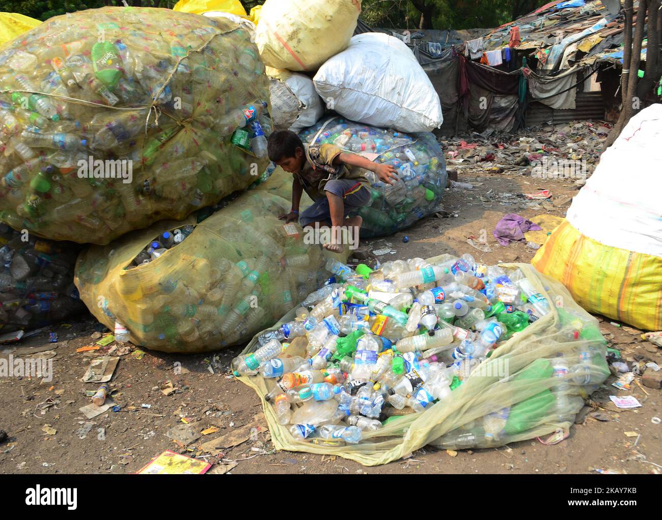 An indian kid plays near a plastic waste dump yard on the banks of ...