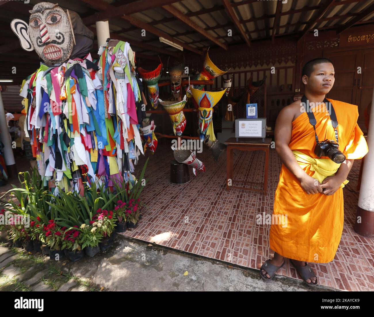 A Buddhist monk stands near a puppet is wear masks representing the ...