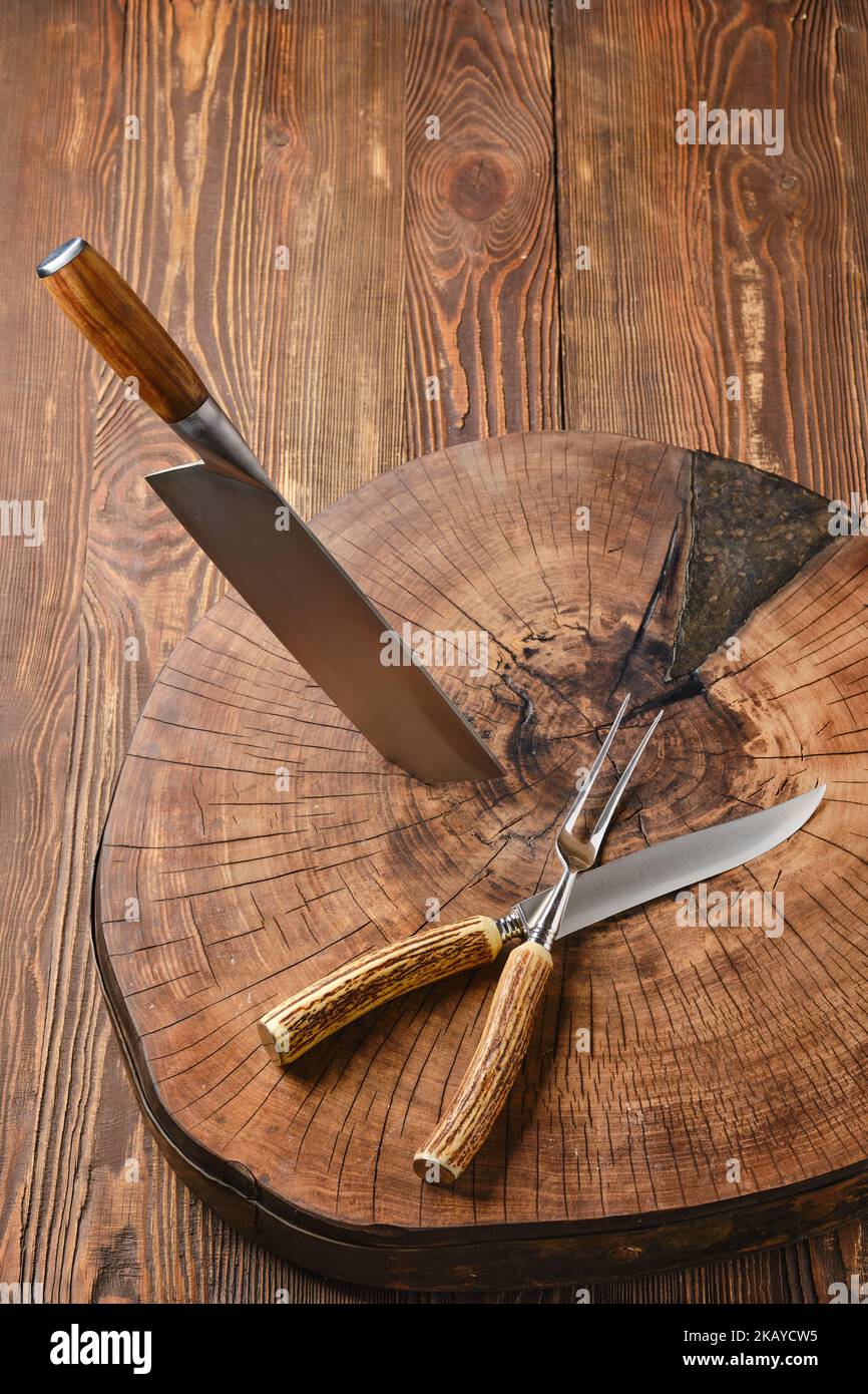 Overhead view of cleaver, fork and knife on wooden stump Stock Photo ...