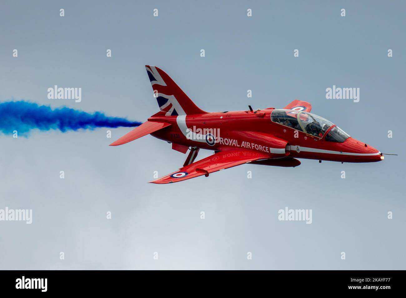 The RAF Red Arrow aircraft flying and ejecting blue smoke Stock Photo ...